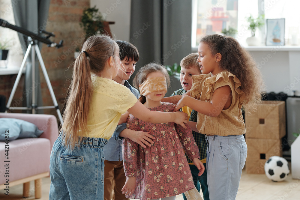 Cute kids surrounding one of girls with her eyes tied during play Stock ...