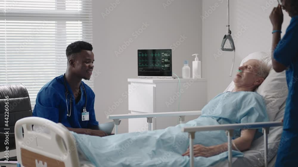 Caring african ethnic medical team at the bedside of an elderly male ...