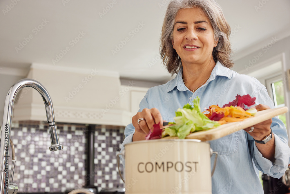 Mature Woman In Kitchen Making Compost Scraping Vegetable Leftovers ...
