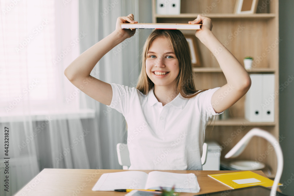 Smiling girl doing homework, taking a break from lessons, putting a ...