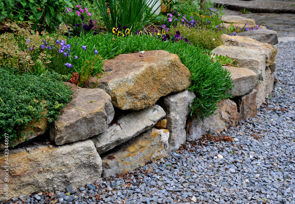 sandstone walls and stones in a flowerbed in a terraced terrain with ...