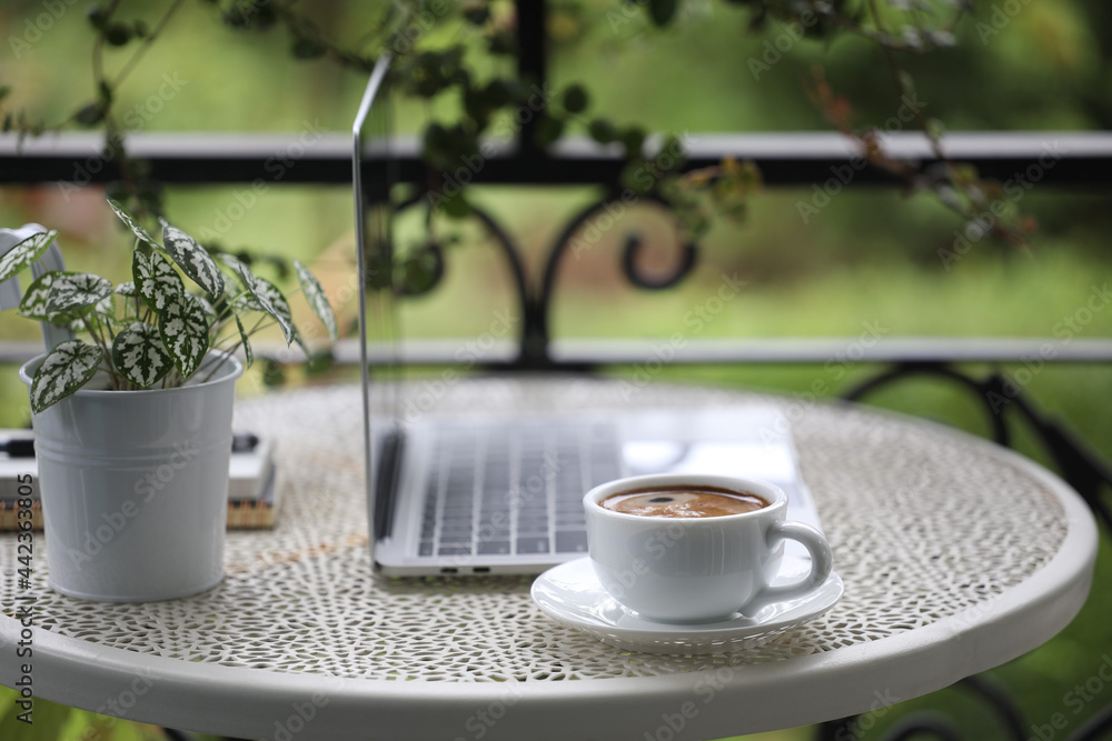 Laptop side view and coffee cup with notebooks on white table outdoor ...