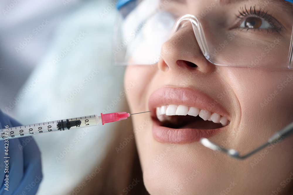 Portrait of young female patient sitting in dentist chair with mouth ...