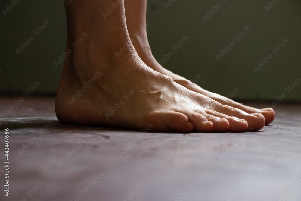 female bare feet on the old wooden floor of the house, feet on the ...