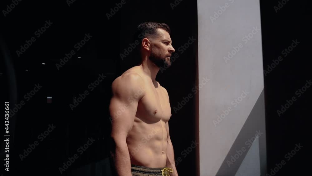 The handsome bodybuilder appears from the shadows, and the light ...