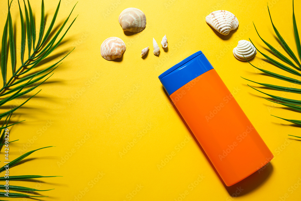 Tube of sunscreen on a yellow summer background with palm leaves and ...