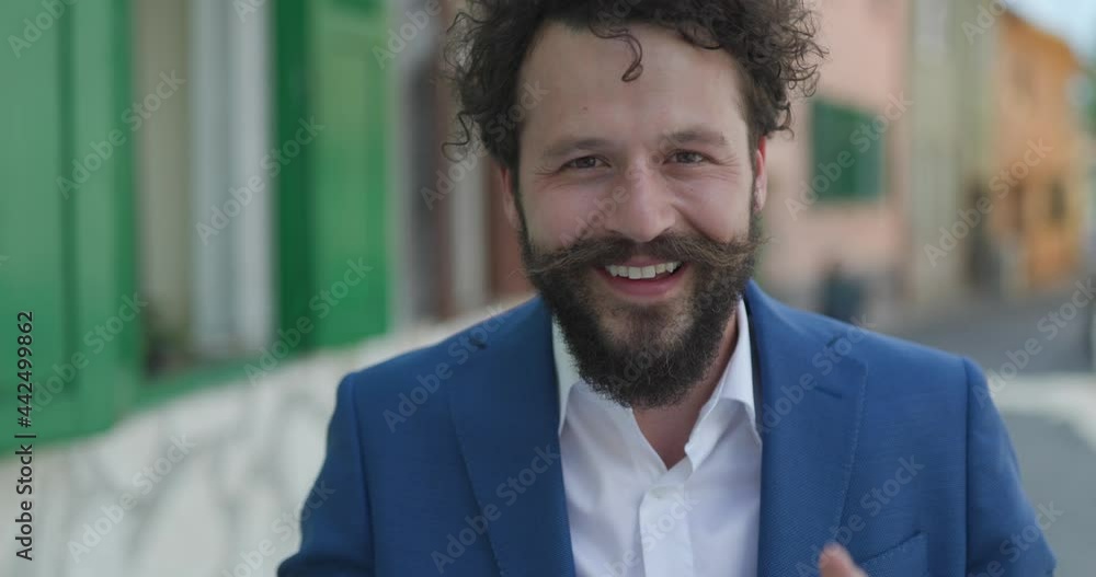 attractive happy man fixing moustache, smiling and laughing, making a ...