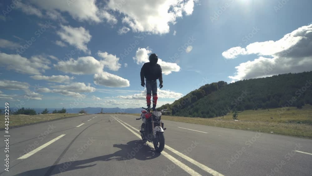 Extreme driving of a motorcycle while standing still on it, male stunt ...