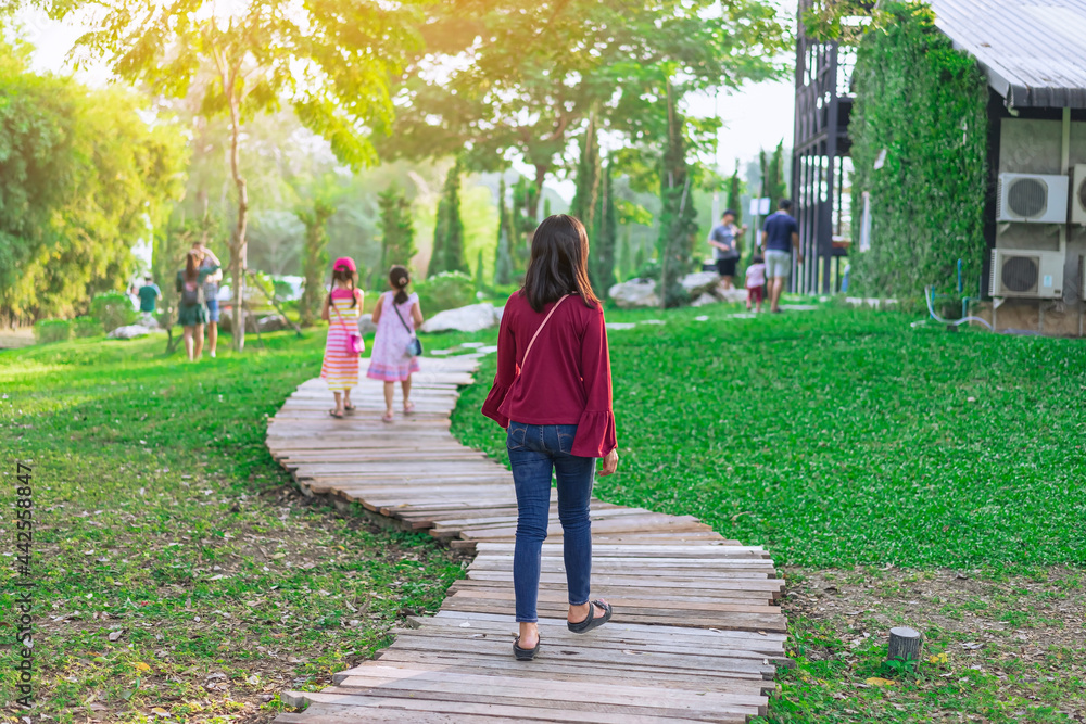 Back view of Asian woman walk alone on pathway through green garden ...