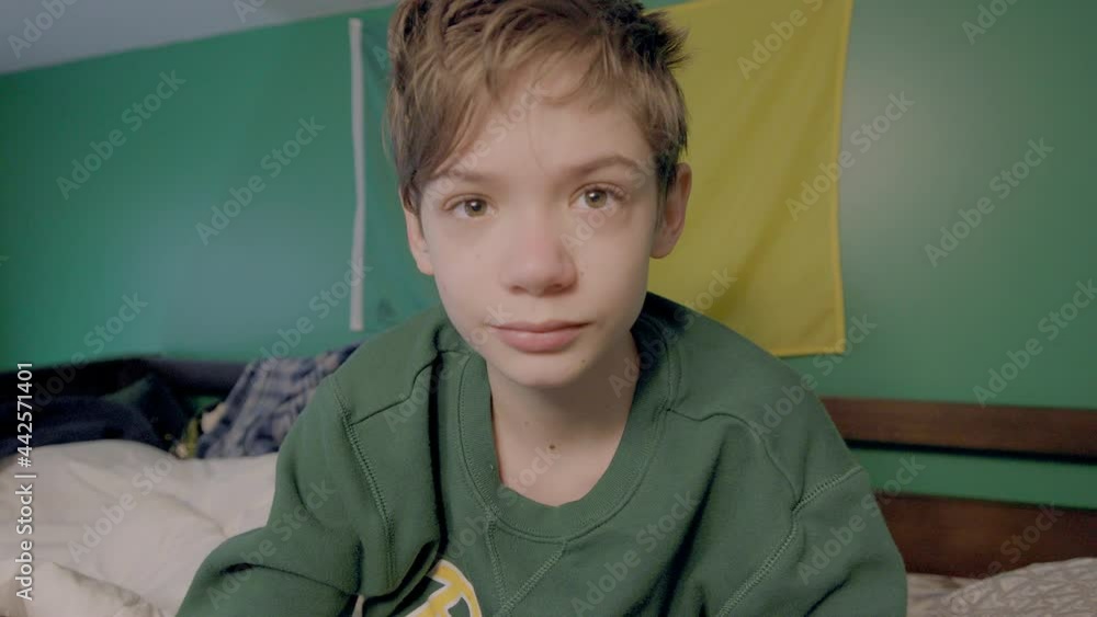 Cute boy in his bunk bed with bedhead and sleepy eyes looks at camera ...