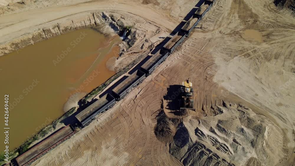Wheel loader loading sand it to the freight train. Mining work in open ...