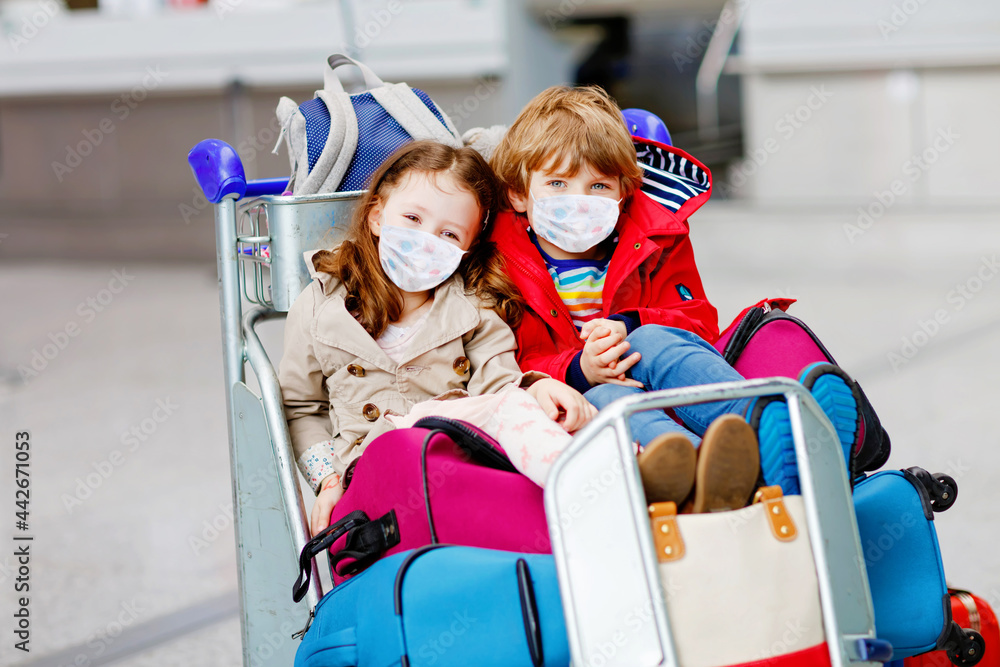 Two little kids, boy and girl wearing medical masks at the airport ...