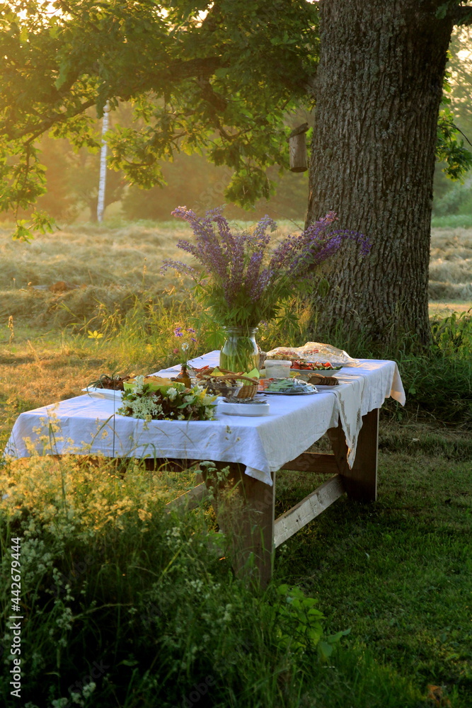 Midsummer food table.Table filled with drinks and food outside in the ...