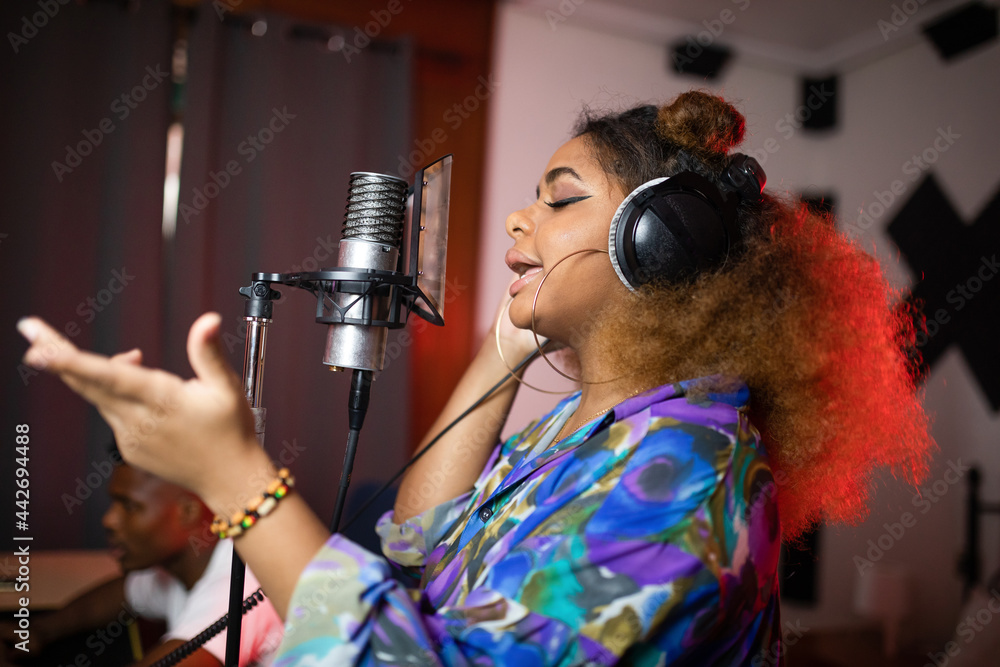 Black artist singing into microphone against producer with laptop Stock ...