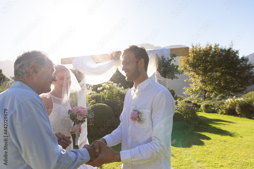 Happy caucasian bride and groom getting married shaking hands with ...