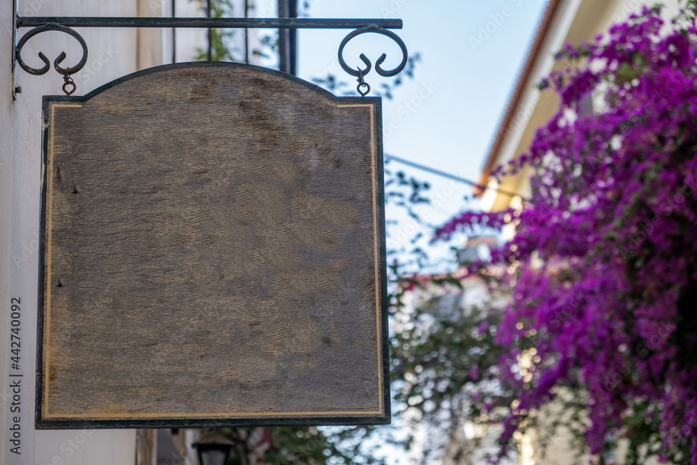 Blank empty wood sign hanging, blue sky and blooming bougainvillea ...