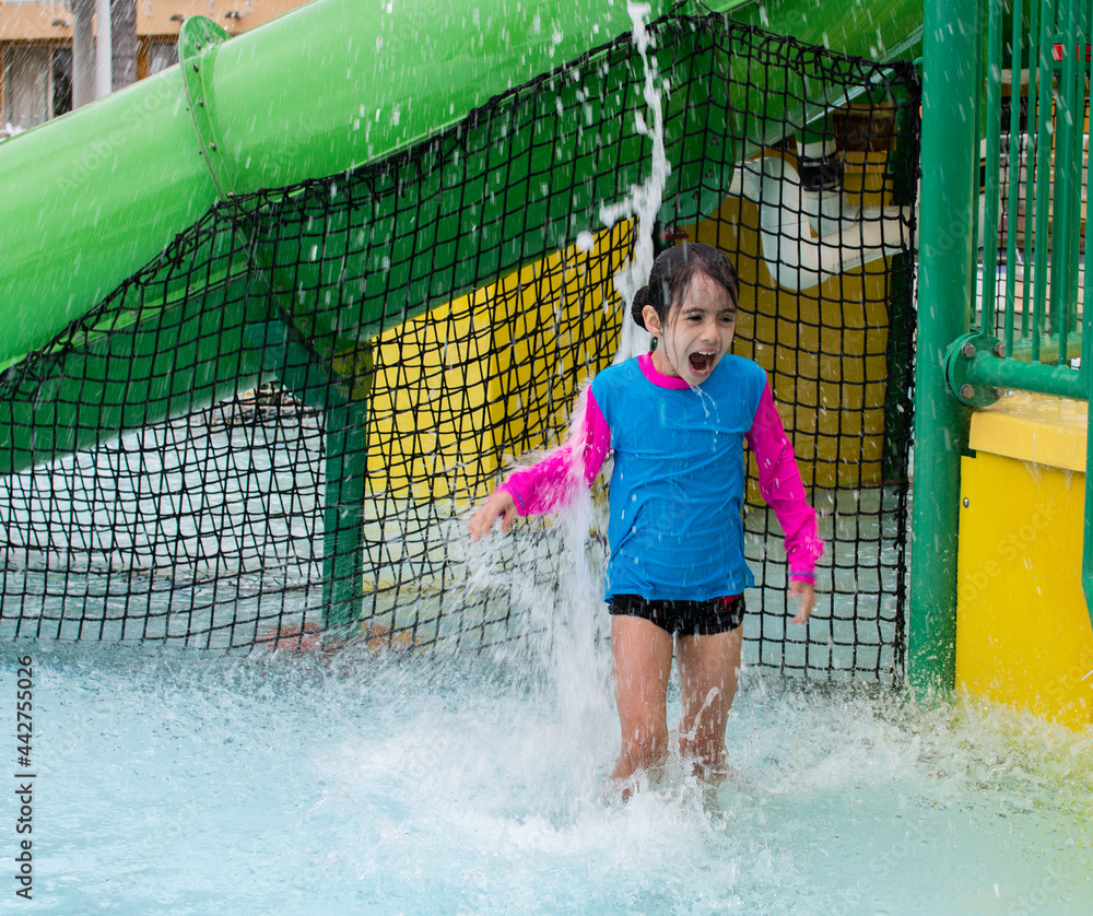 A girl plays in a stream of water from the pool at the water park ...