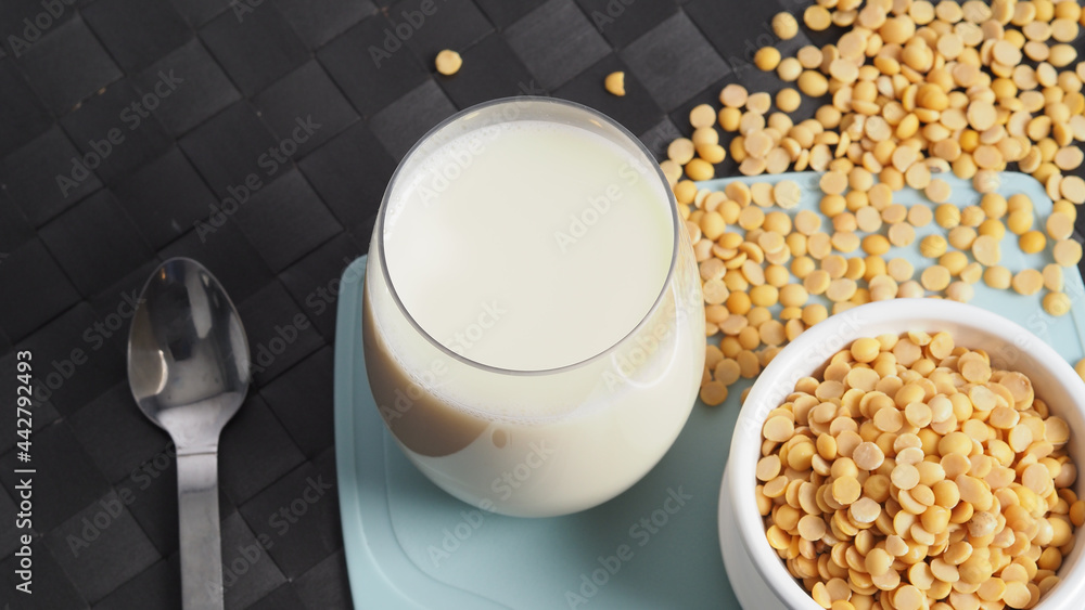 Soy milk with no sugar added in a glass on a green color plastic plate ...