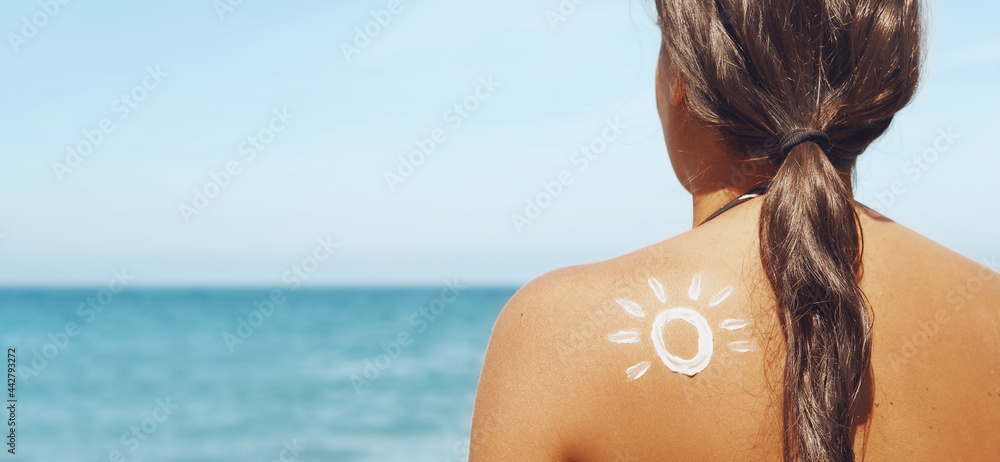 Sun drawn with sunscreen on the shoulder of a female with tanned skin ...
