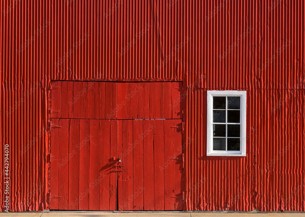 Exterior of bright red barn with closed wooden doors and one black ...