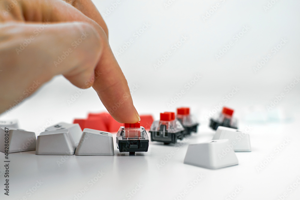 Mechanical keyboard switch on a white background. The person presses ...