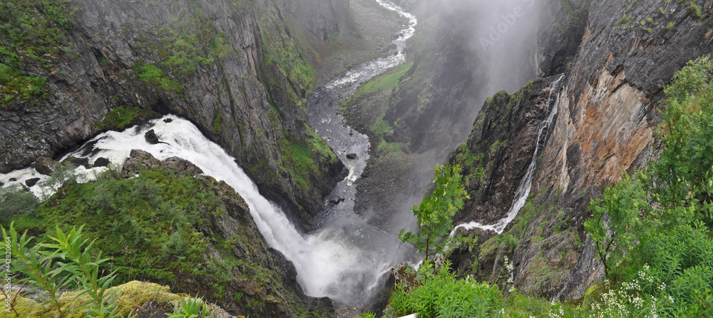 Two waterfalls flowing into a deep valley opposite each other ...