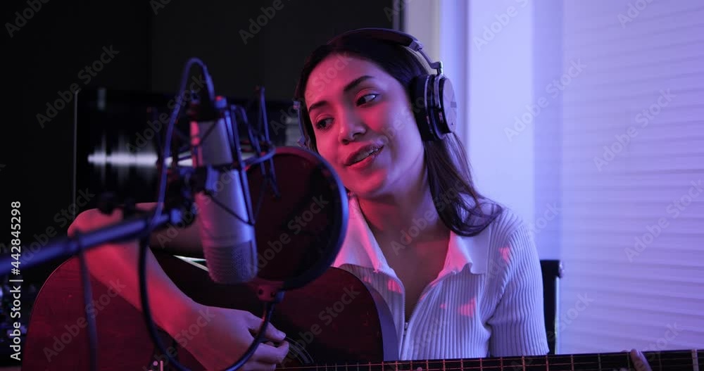 Female singer playing acoustic guitar and singing a song. Asian woman performing vocal artist ...
