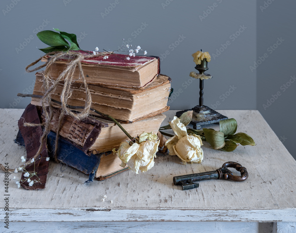 On the table is a pile of old books, tied with a rope. Two withered ...