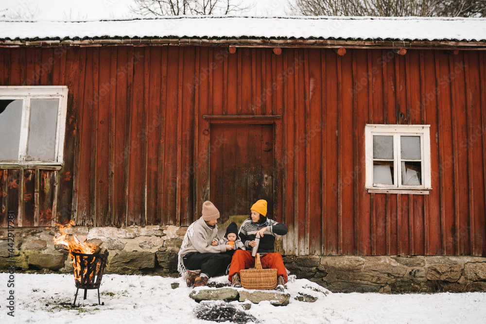 Mammor med barn sittande utanför stuga i snön Stock Photo | Adobe Stock