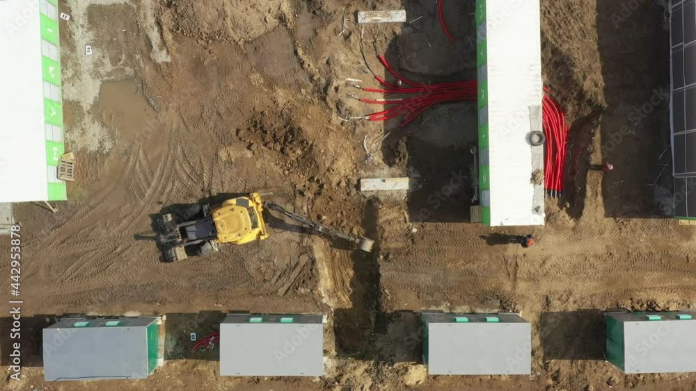 Aerial of powerful yellow excavator digging trench with bucket. Laying ...