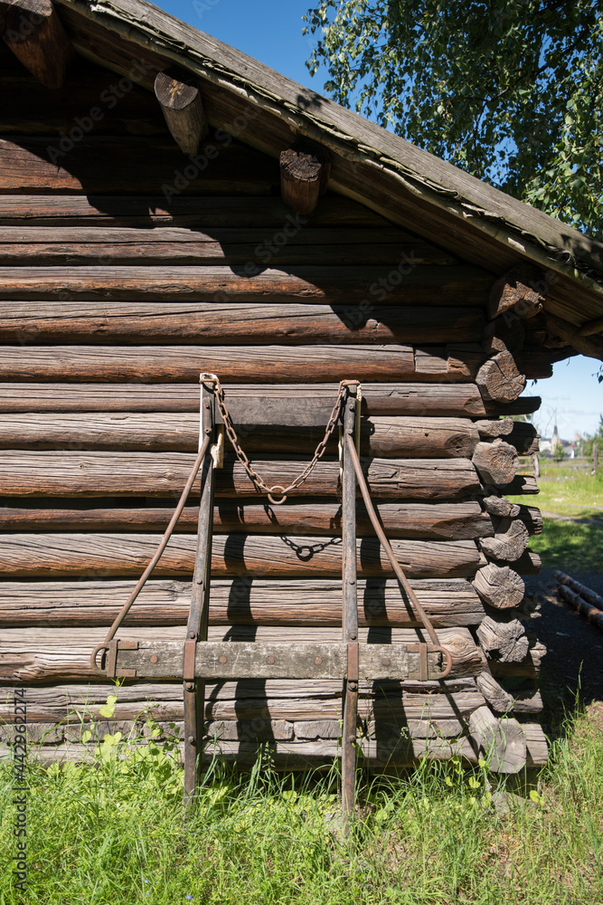 Old sledge leaning on a log house wall at display in a park in ...