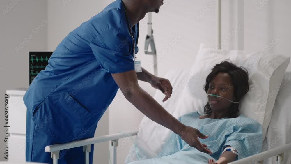african-american woman resting in hospital bed after surgery talking to ...