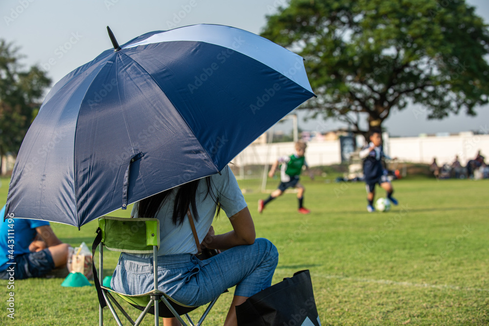 Parents sitting and watching their son playing football in a school ...
