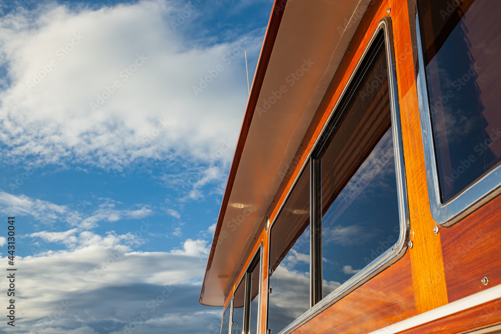 Wooden hull of a yacht with rectangular portholes against the sky, side ...