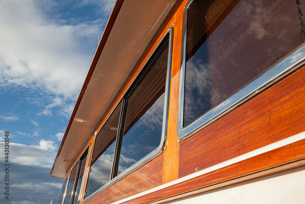 Wooden hull of a yacht with rectangular portholes against the sky, side ...