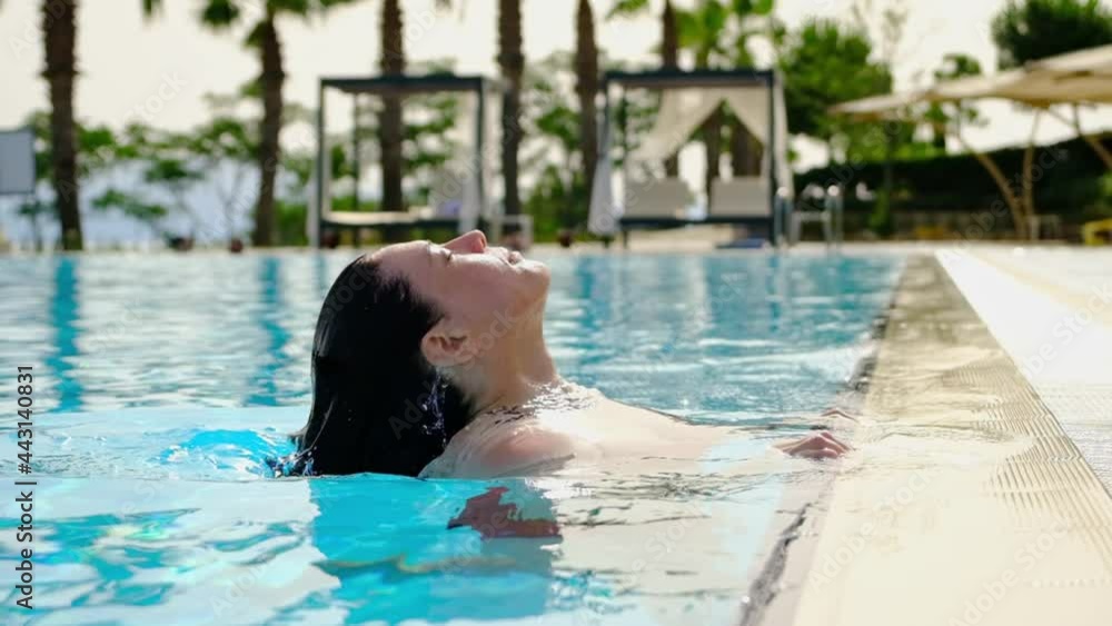 The beautiful girl comes up from pool and from it water flows down ...