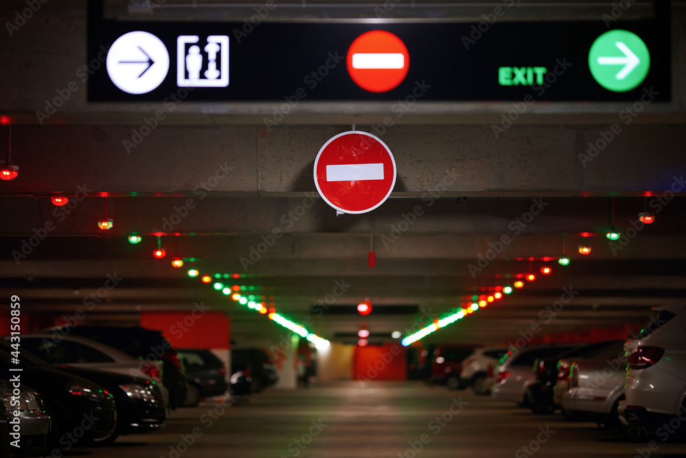 Stop sign on full car parking garage, parking lights on background ...
