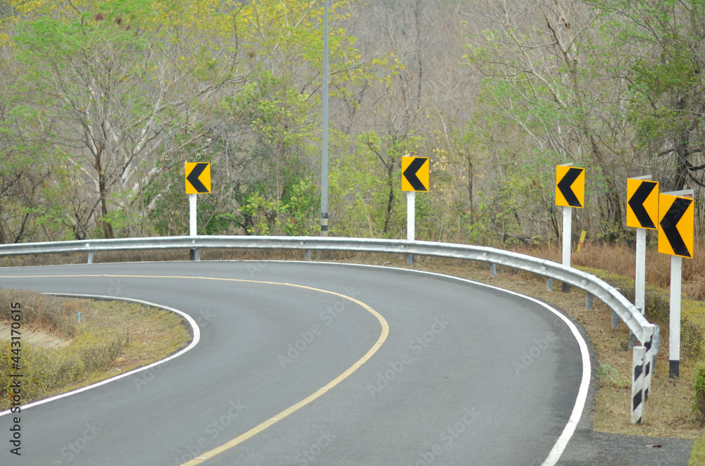 Road signs warn of a sharp turn on a narrow road. Stock Photo | Adobe Stock