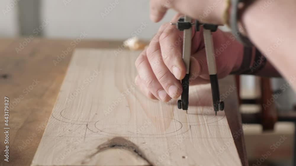A carpenter marks a pine wooden plank with a compass. woodworker using ...