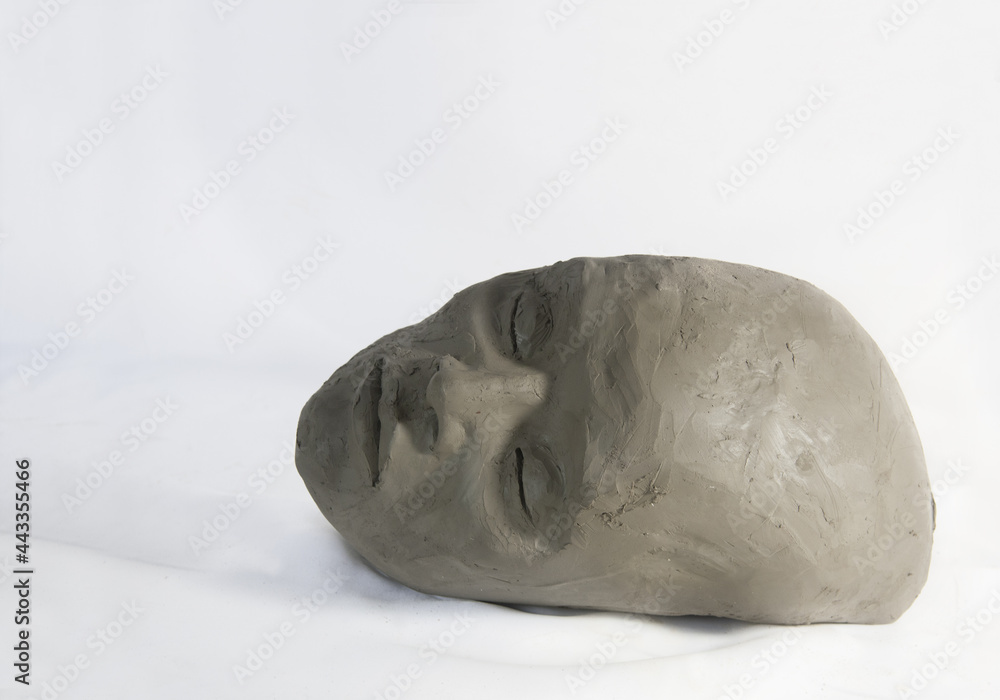 Clay sculpture, with closed eyes. face with shadows, lying on white ...