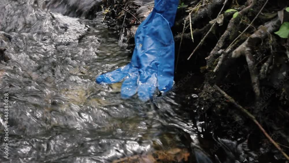 medical blue mask and rubber glove float on the water surface in a ...