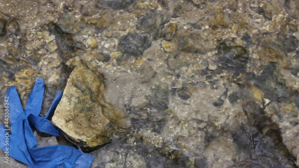 medical blue mask and rubber glove float on the water surface in a ...