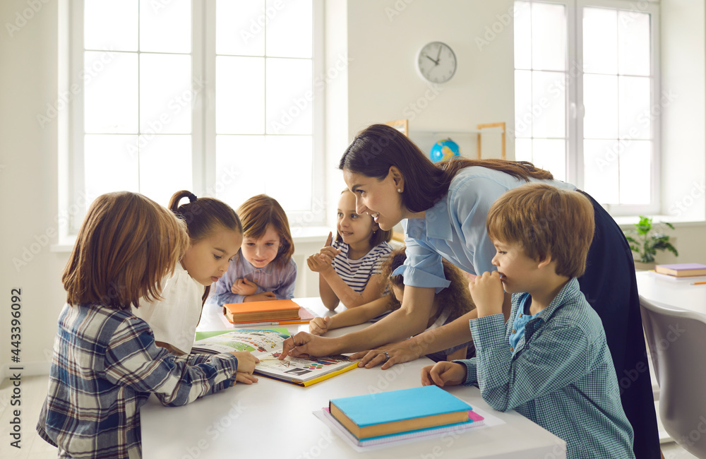 Happy teacher and children reading book together. Group of school kids ...