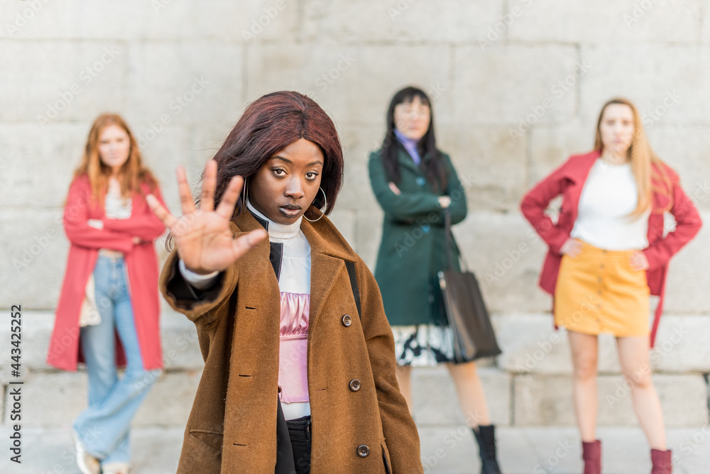 Black woman showing stop sign against company of devise females Stock ...