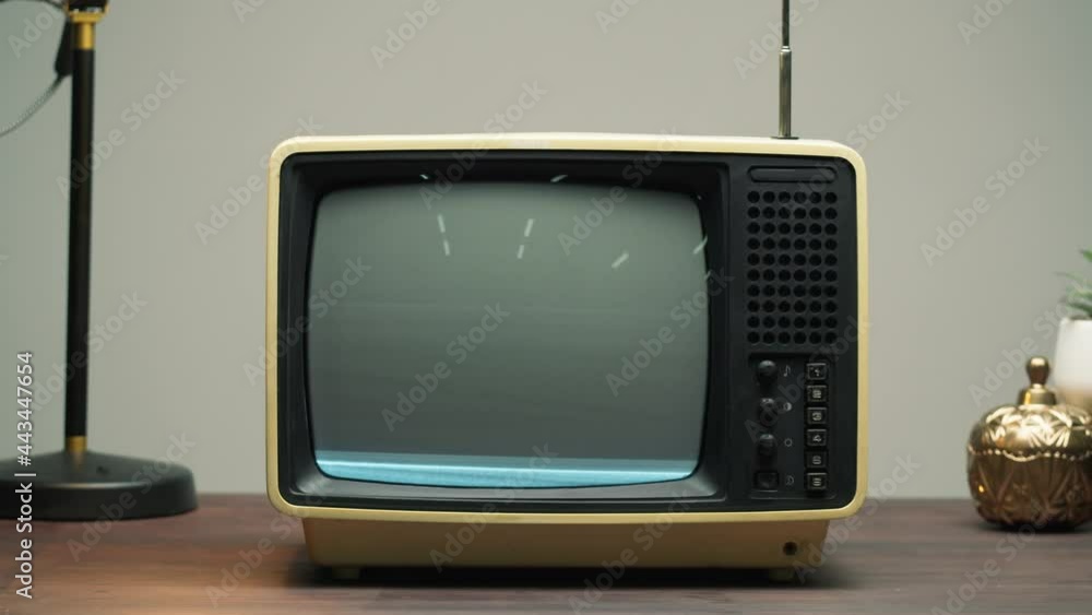 Turning on old retro television with antenna on grey background ...