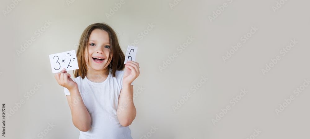 cute kid girl in mustard dress learns the multiplication table on beige ...