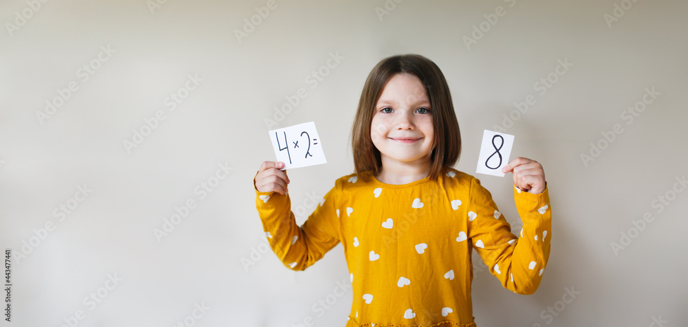 cute kid girl in mustard dress learns the multiplication table on beige ...