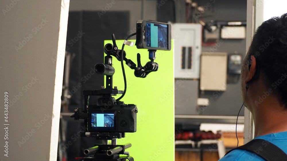 Video Camera set up on tripod and professional camera cage rig. Behind ...