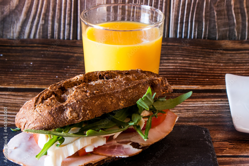 Bocadillo de vegetales, tomate, queso mozzarella y jamón, junto a un ...