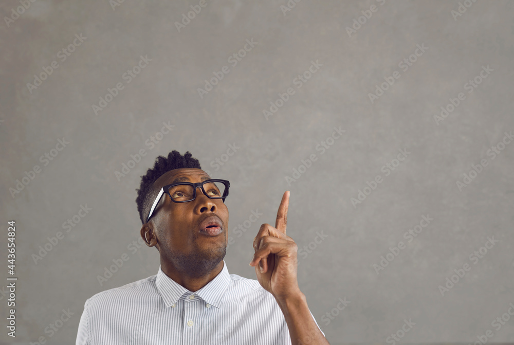 Handsome young black man in white shirt and stylish glasses looks up ...